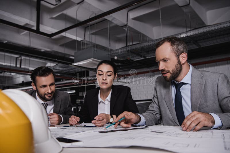 Architects and Engineers in Suits Working at Table with Blueprints ...