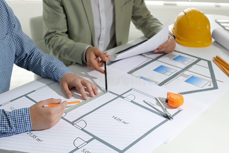 Architects Working with Construction Drawings at Table in Office ...