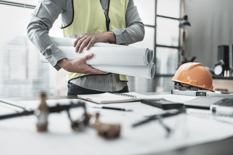 Architect, Engineer Holding Paper Roll Drawings in the Office. Building ...