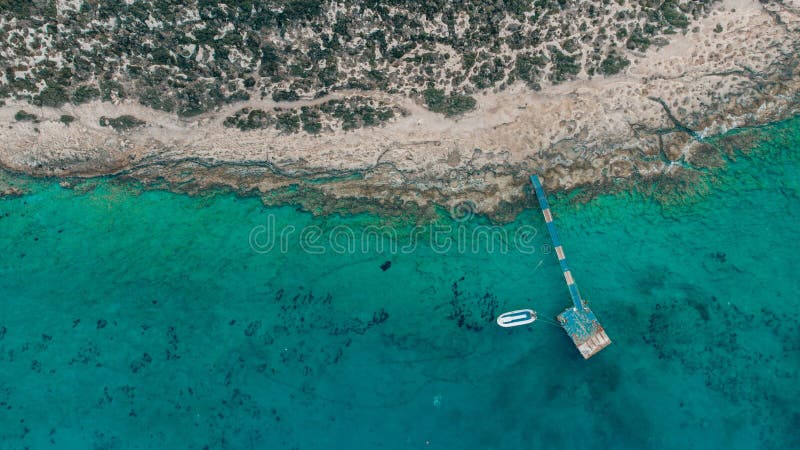 Arial Shot of Blue Clear Sea with Blue Tiny Boat on it and the Stone ...