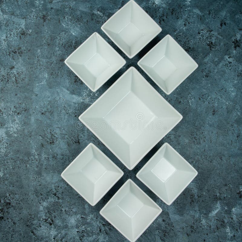 Array of Square Ceramic Plates Arranged in a Neat Pattern on a Blue ...