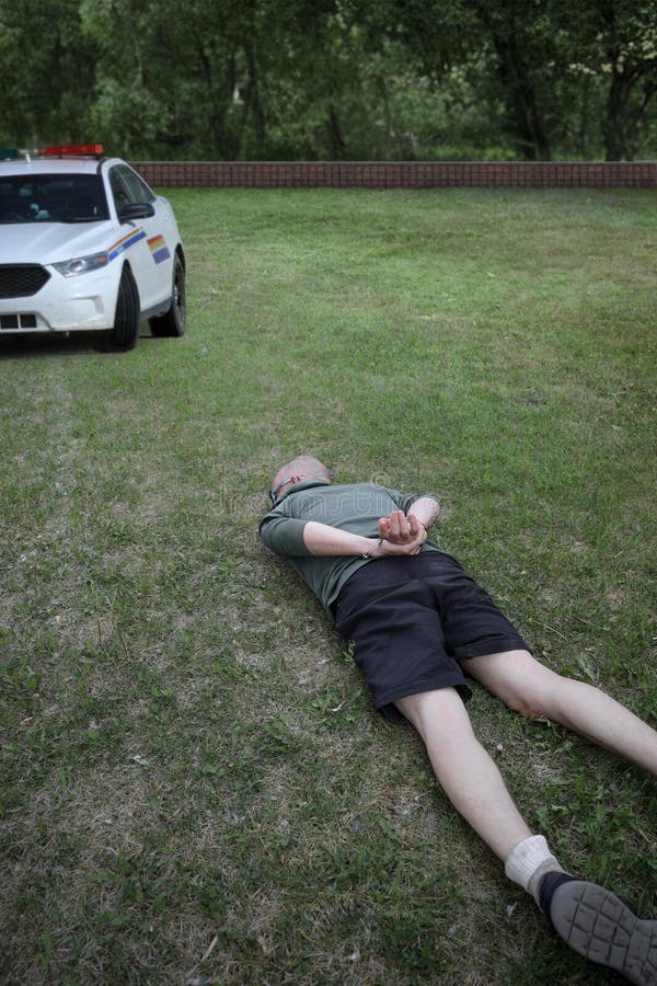 Arrested Man in Handcuffs Laying Face Down on the Grass Stock Image ...
