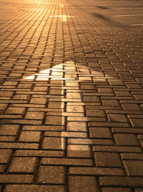 Arrow on a Road Tile in the Rays of the Setting Sun Stock Image - Image ...