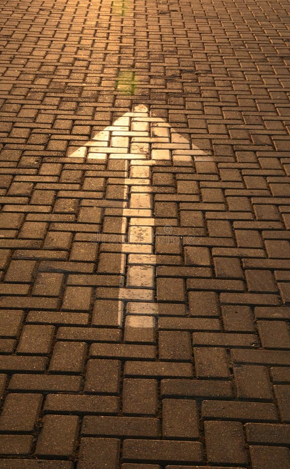 Arrow on a Road Tile in the Rays of the Setting Sun Stock Photo - Image ...