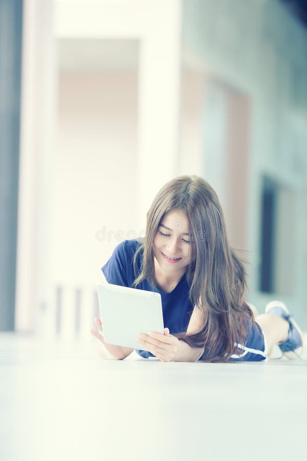 Asia Smile Girl Lying on Floor and Looking into Tablet Computer Stock ...