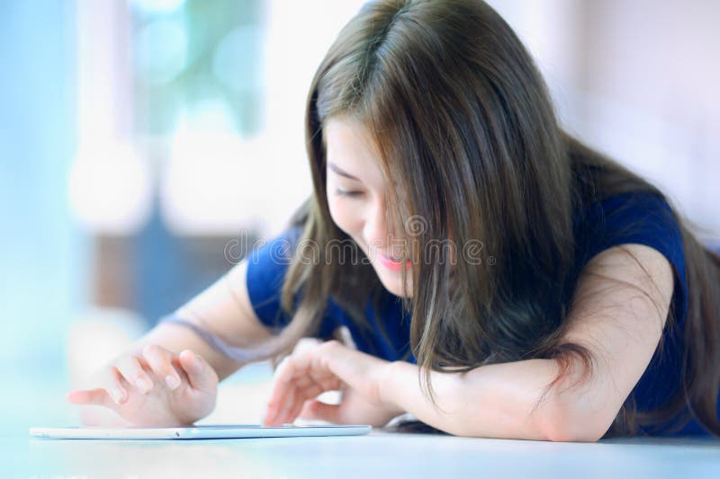 Asia Smile Girl Lying on Floor and Looking into Tablet Computer Stock ...