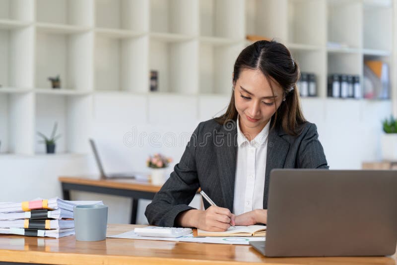 Asian Accountant Using Calculator while Taking Notes on Office Desk ...