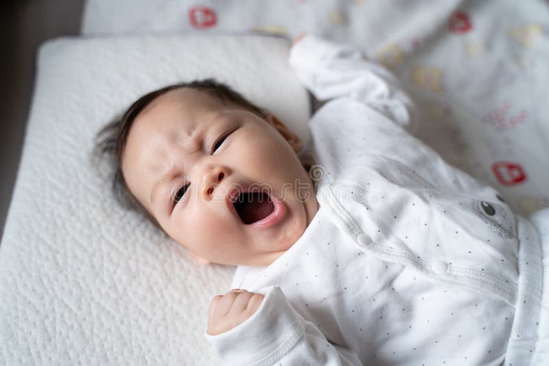 Asian Baby Infant in White Lie Down on Bed with Face Expression. Facial ...
