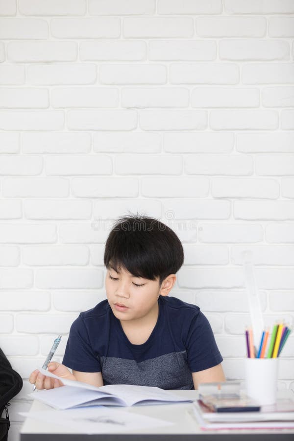 Asian Boy Doing Homework Near White Brick Wall Stock Photo - Image of ...