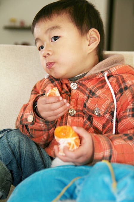 Asian Boy Eating Orange on Sofa Stock Photo - Image of childhood ...
