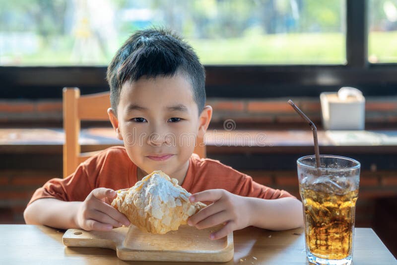 Asian Boy Eating Sweet Croissant in Restaurant with Beverage Stock ...
