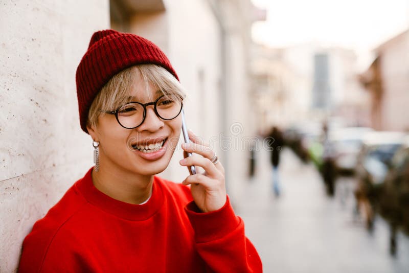 Asian Boy Laughing and Talking on Mobile Phone by Wall Stock Image ...