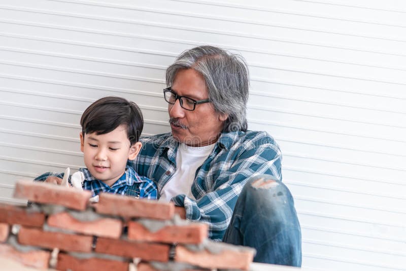 Asian Boy Learning How To Build a Brick Wall from His Construction ...