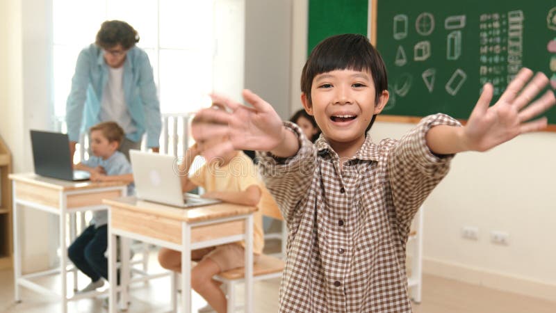 Boy Looking at Camera while Waving Hands and Standing at Blackboard ...