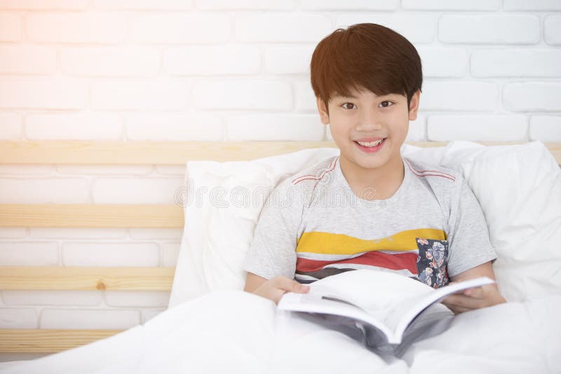 Asian Boy Rest on the Bed and Reading Book Stock Photo - Image of ...