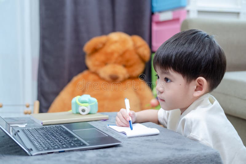 Asian Boy Taking Notes on Paper while Studying Online on Laptop Stock ...
