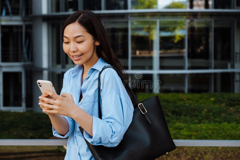 Asian Brunette Woman Laughing and Using Mobile Phone Stock Photo ...
