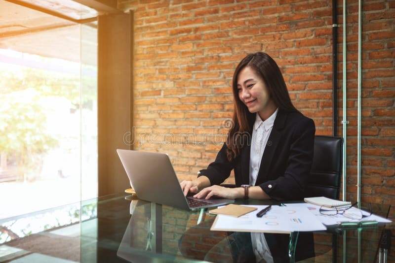 An Asian Businesswoman Using and Typing on Laptop while Working in ...