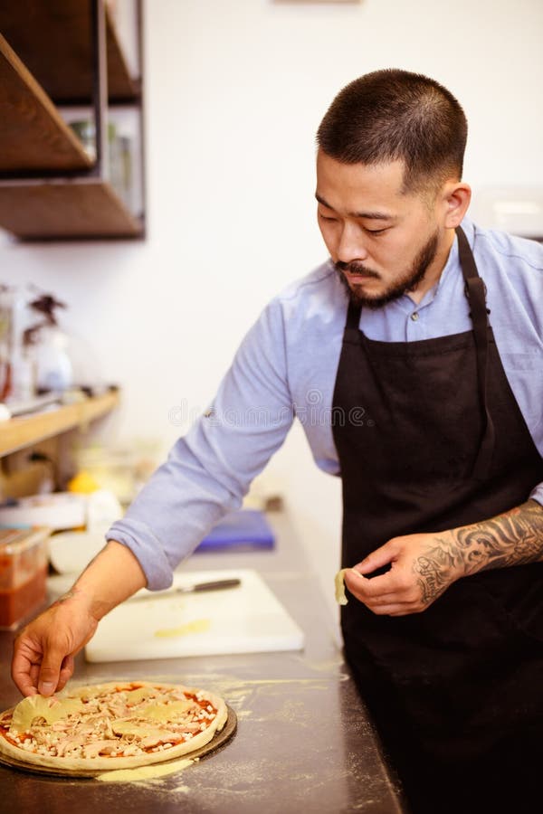 Asian Chef Putting Pineapple on Raw Pizza while Cooking on Cafe Kitchen ...