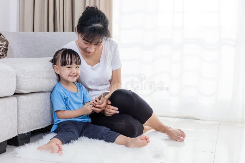 Asian Chinese Mother and Daughter Using Smartphone on the Floor Stock ...