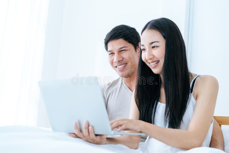 Asian Couple on Bed Using Laptop Together Stock Photo - Image of ...