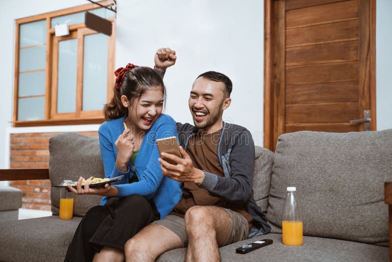 Asian Couple Laughing While Looking At Cell Phone Screen Together Stock