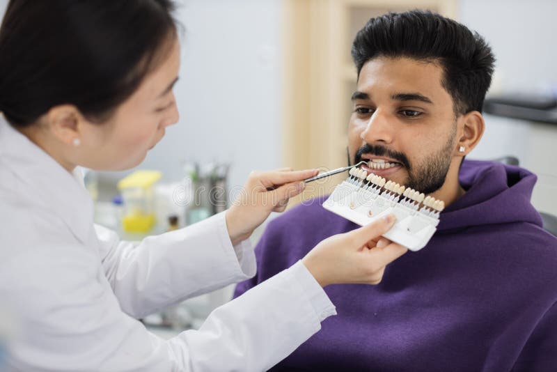 Asian Dentist Checking and Selecting Color of Young Bearded Man Teeth ...