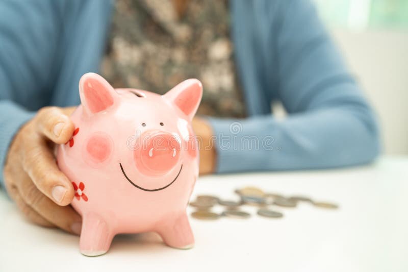 Asian Elderly Woman Putting Coin into Pink Piggy Bank for Saving Money ... Asian Elderly Woman Putting Coin into Pink Piggy Bank for Saving Money ...