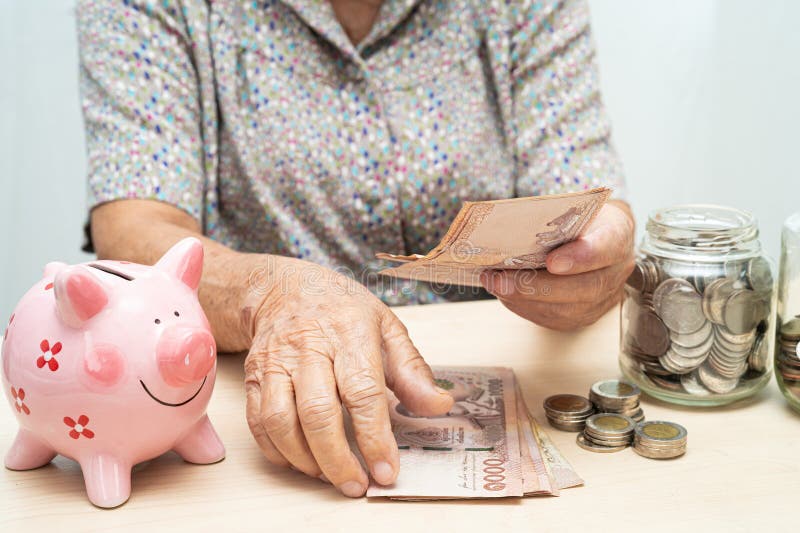 Asian Elderly Woman Putting Coin into Pink Piggy Bank for Saving Money ... Asian Elderly Woman Putting Coin into Pink Piggy Bank for Saving Money ...