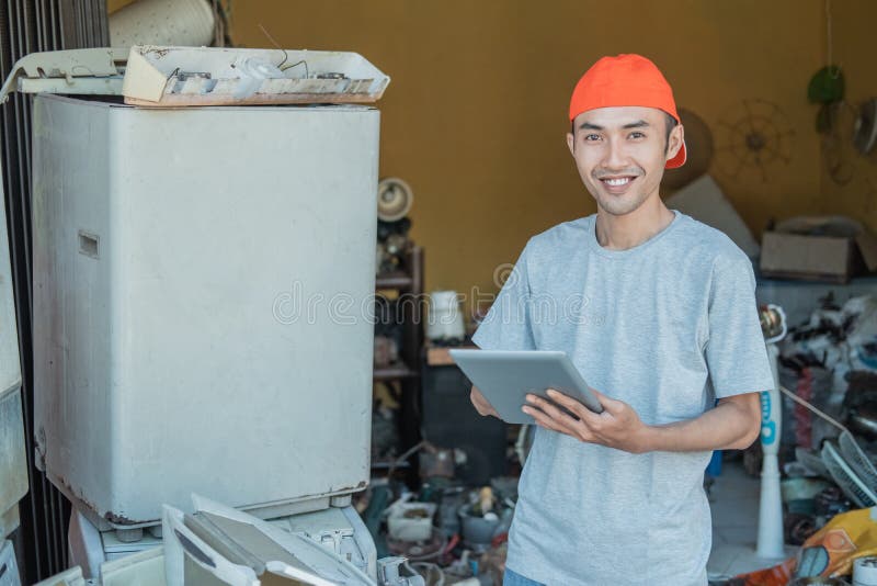 Asian Electronics Repairman Smiles at the Camera while Using His Tablet ...