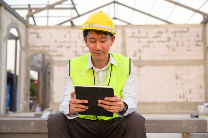 Asian Engineer Man is Wearing a Protective Helmet on Head, Using Tablet ...
