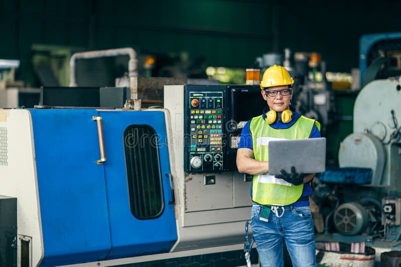 Asian Engineer Working Programming the Machine in Factory with Laptop ...