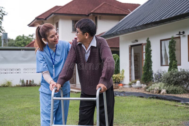 Asian Female Caregiver Helps Senior Man Walk A Senior Using A Walker Is
