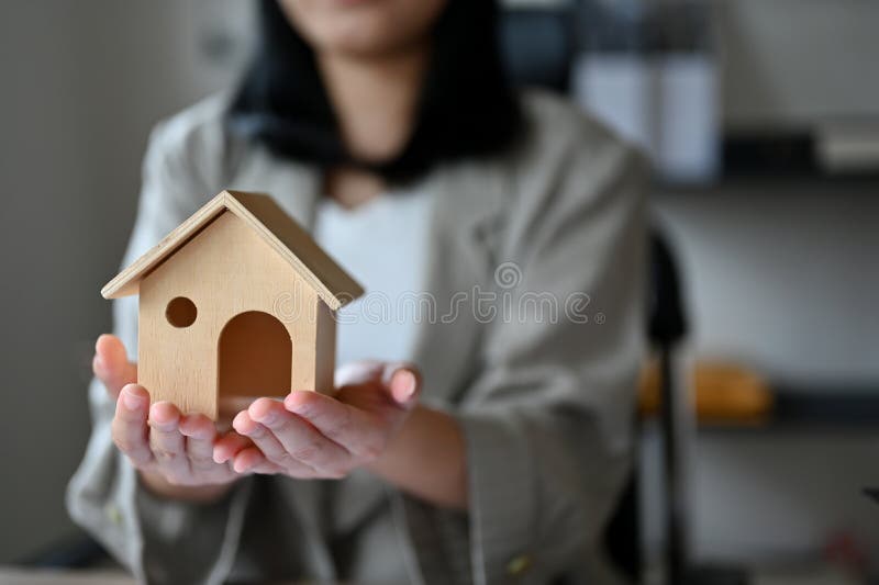 Asian Female Real Estate Agent Or Realtor Showing A House Model On Her