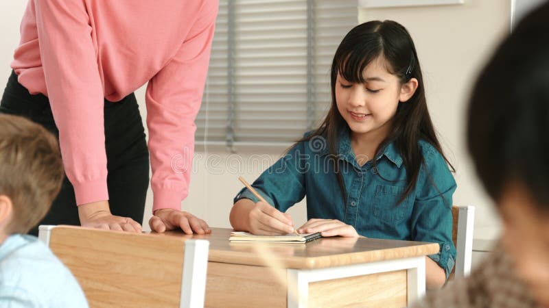 Asian Girl Writing or Taking a Note while Teacher Checking Classwork ...