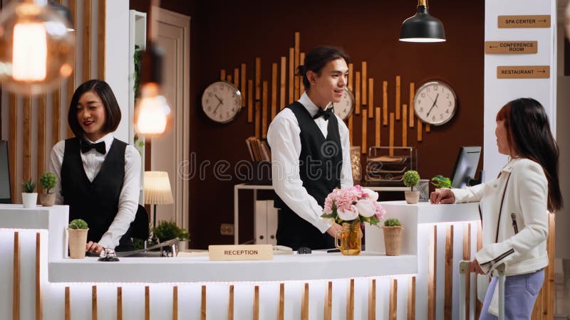 Asian Guest Arriving at Hotel and Asking about Room Reservation Stock ... Asian Guest Arriving at Hotel and Asking about Room Reservation Stock ...