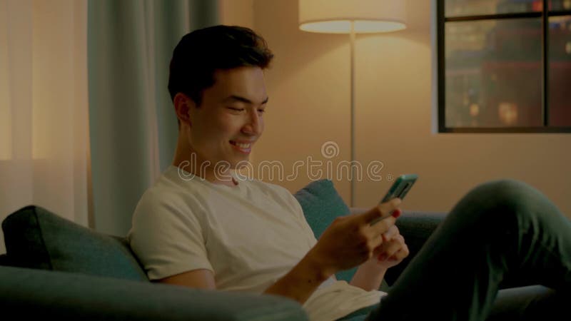 Asian Guy Types Message on Smartphone and Laughs Chatting Stock Footage ...