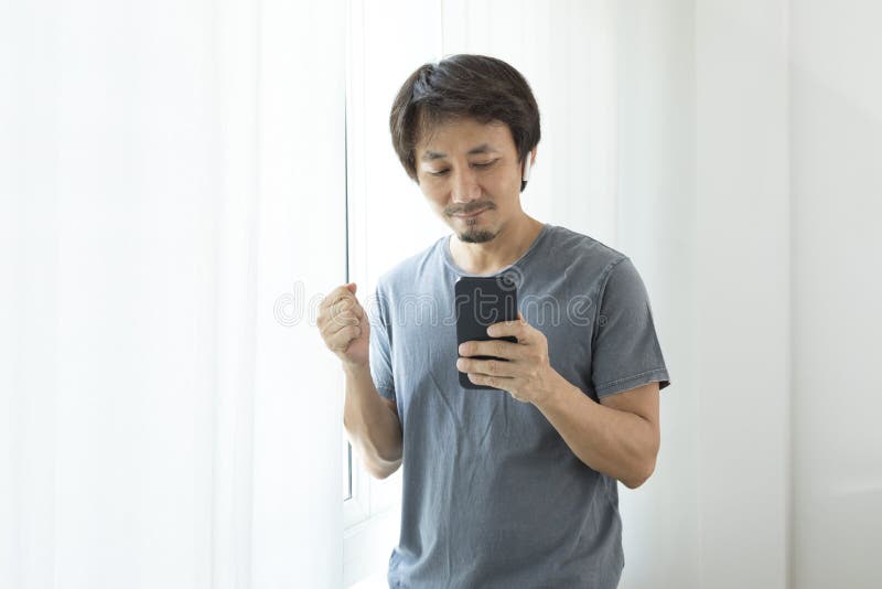 Asian Guy Using Voice Assistant on Cellphone with Earpod by the Window ...