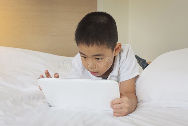 Asian Little Boy Using Tablet Computer in Bed Stock Photo - Image of ...