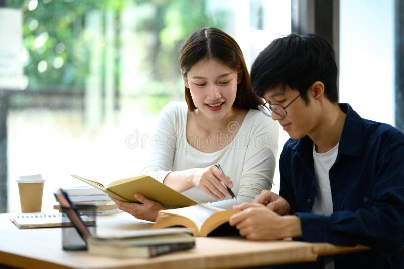 Asian Male and Female Student Collaborating on a Group Assignment in Co ...