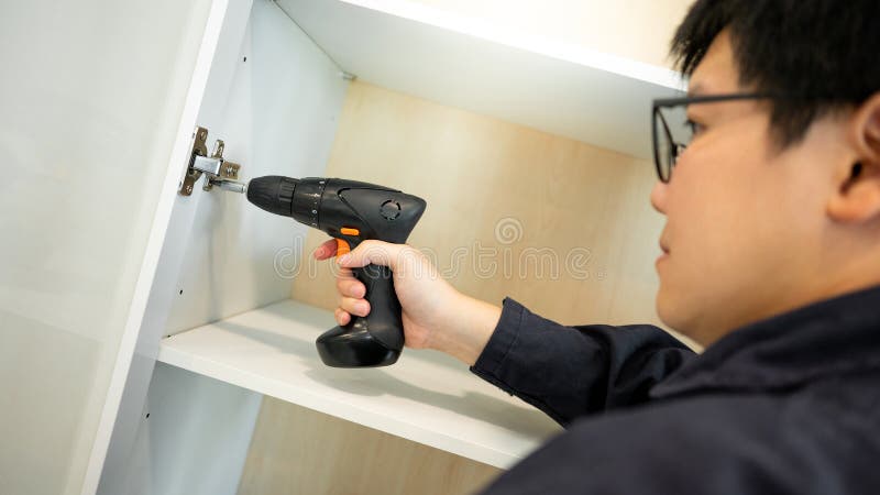 Asian Male Furniture Assembler Using Electric Drill Screwdriver Stock