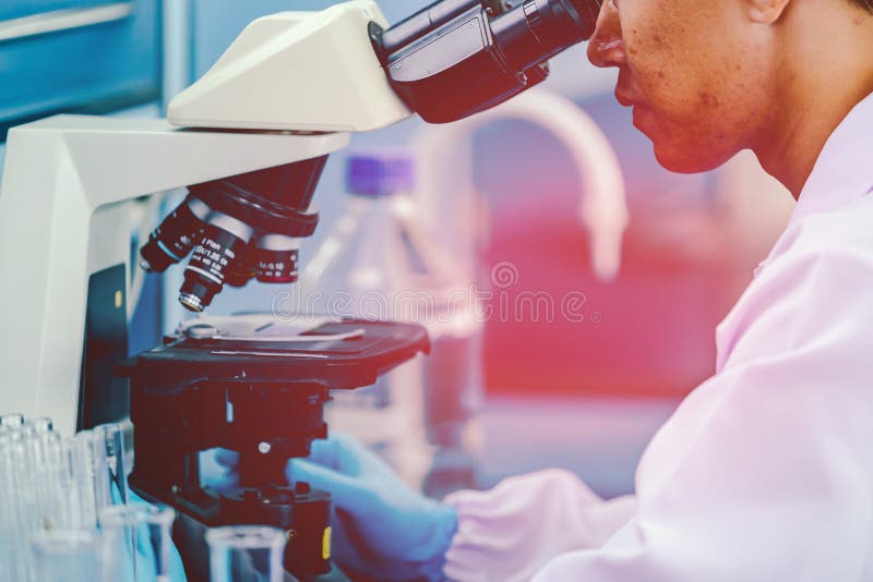 Asian Male Medic in Uniform Working with Microscope Making Analysis at the Laboratory Office ...