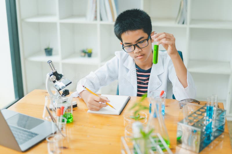 Asian Male Science Students Looking through a Microscope and Tests of ...