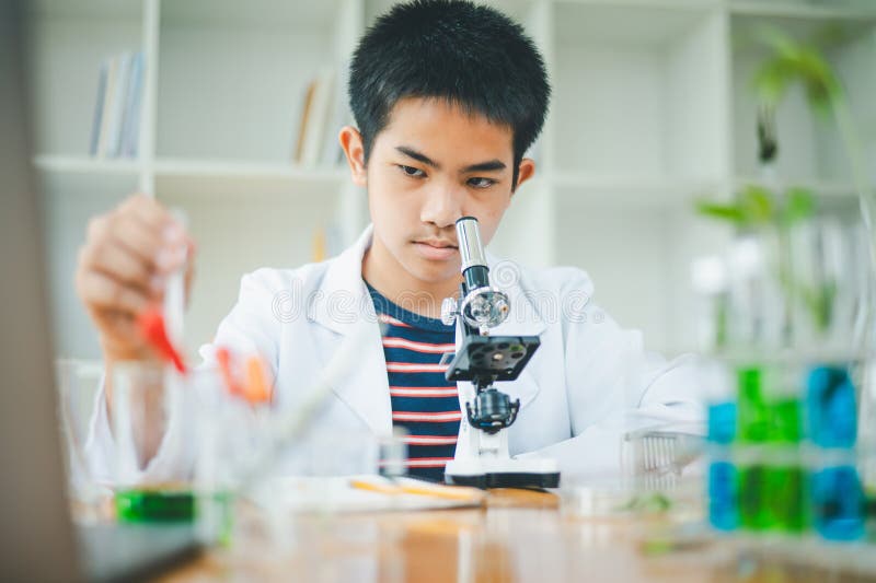 Asian Male Science Students Looking through a Microscope and Tests of ...