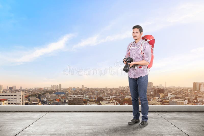 Asian Man with a Backpack Holding a Camera To Take Pictures on the ...