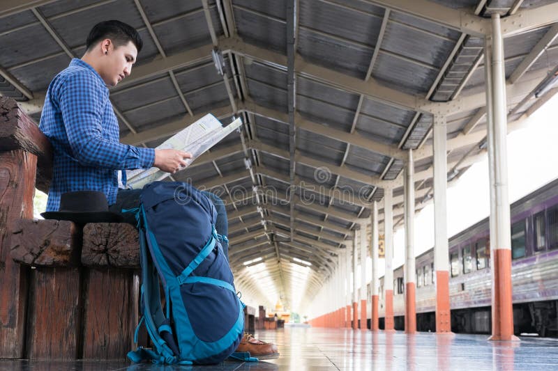 Asian Man with Backpack Sitting on Platform at Train Station. Ba Stock ...