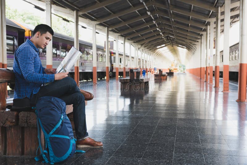 Asian Man with Backpack Sitting on Platform at Train Station. Ba Stock ...