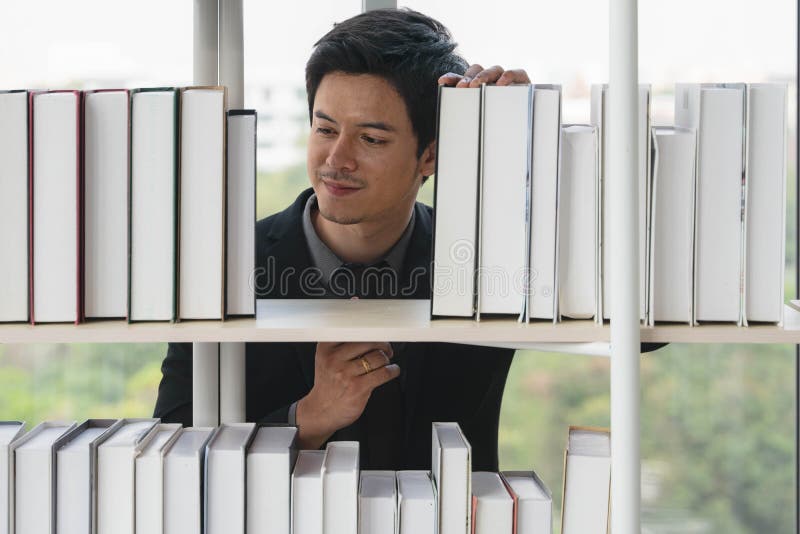 Asian Man at Book Shelf in Library Searching and Reading Book Stock ...