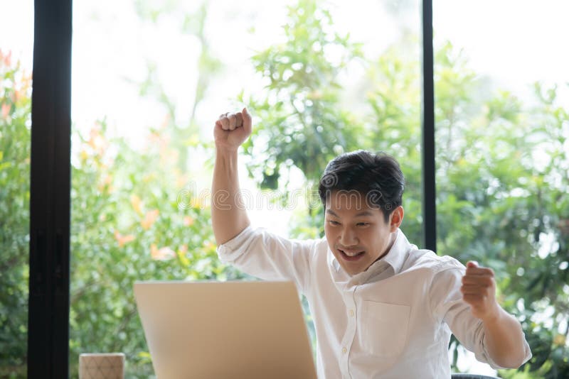 Asian Man Celebrating Success while Working on Laptop at Home. Stock ...