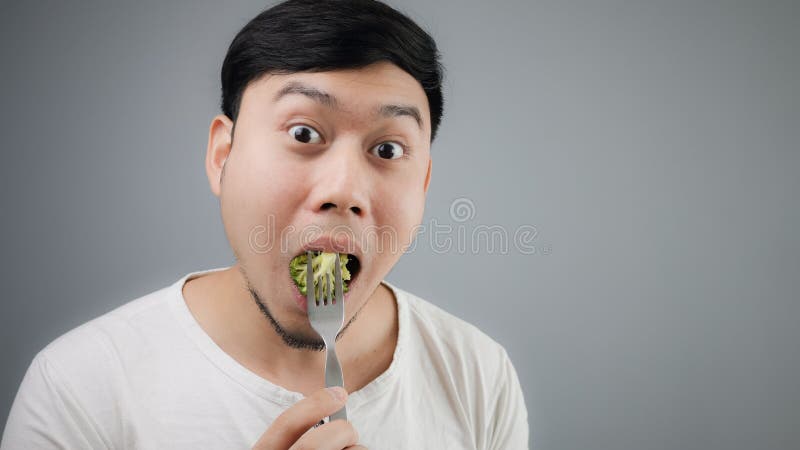 An Asian Man Eats Broccoli. Stock Image - Image of holding, food: 57158733